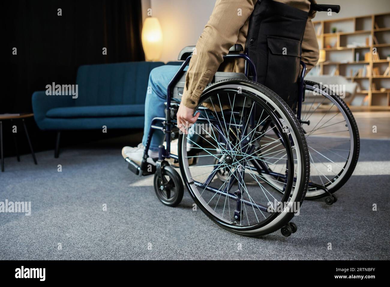 Ein behinderter Mann sitzt im Rollstuhl. Er hält seine Hände am Lenkrad ...