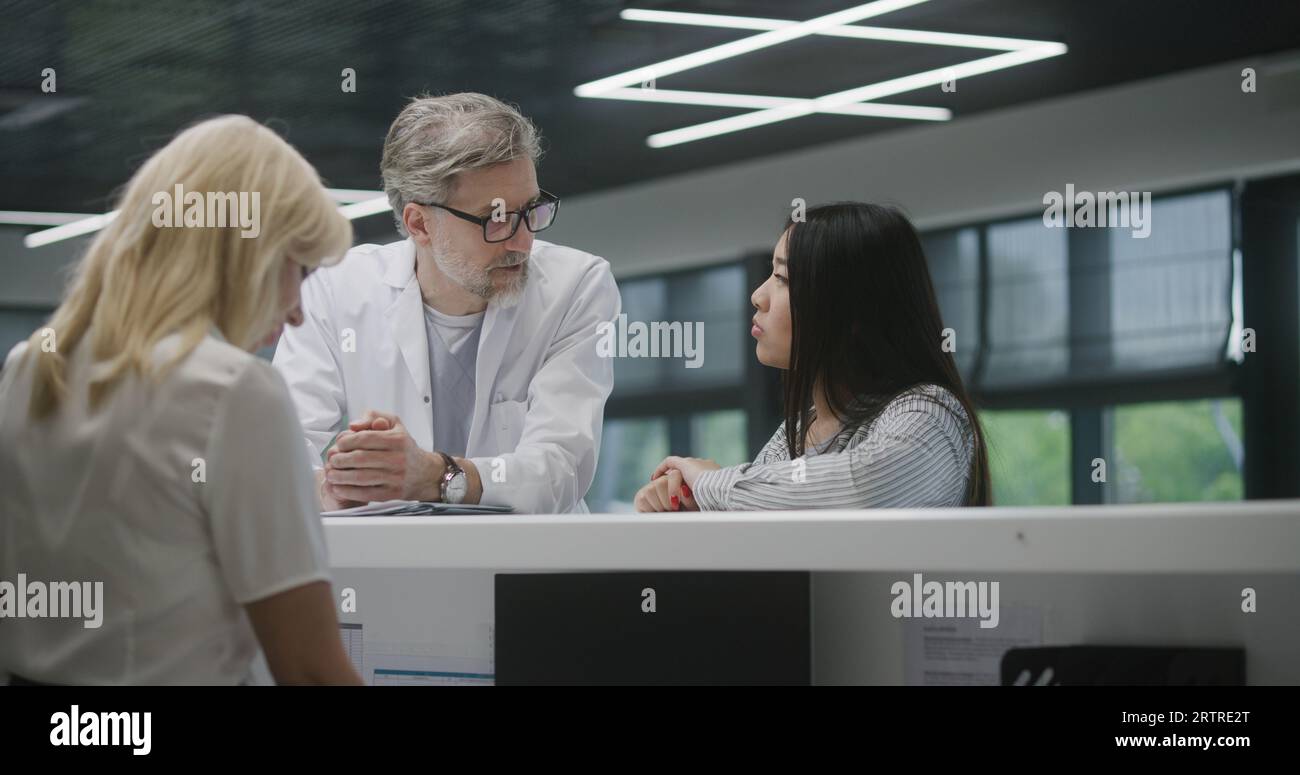 Asiatische Frau steht in der Nähe der Rezeption im Wartezimmer des ...