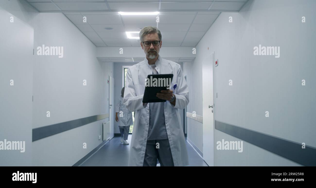 Die Ärztin geht mit dem alten Patienten in die Arztpraxis. Der ältere ...