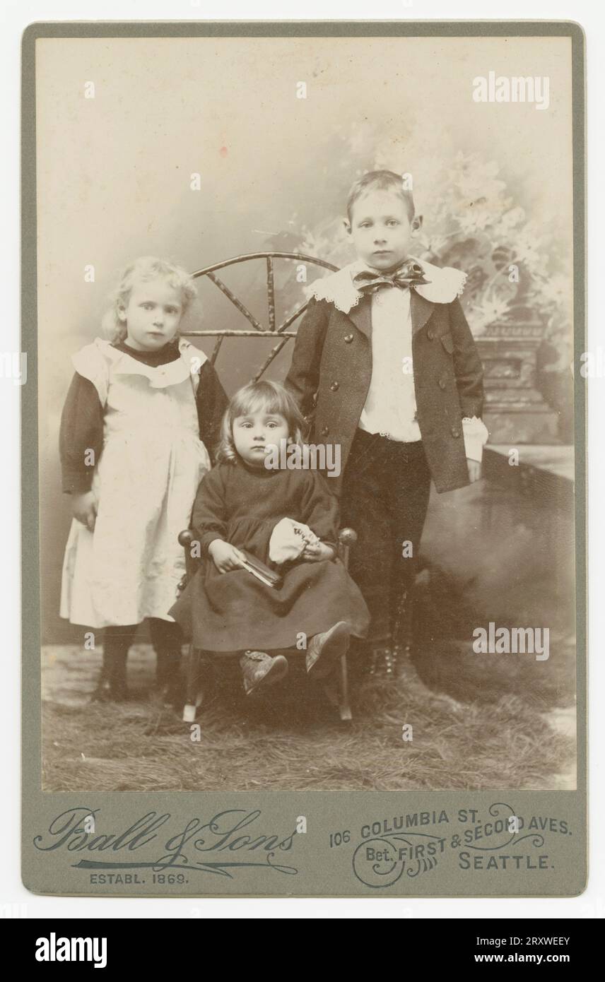 Ein Schwarzweißfoto von drei kleinen Kindern, das im Ball & Sons Studio ...