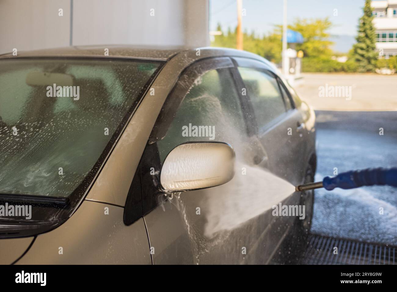 Der Mann in der Autowaschanlage wäscht das Auto. Waschen des Fahrzeugs ...
