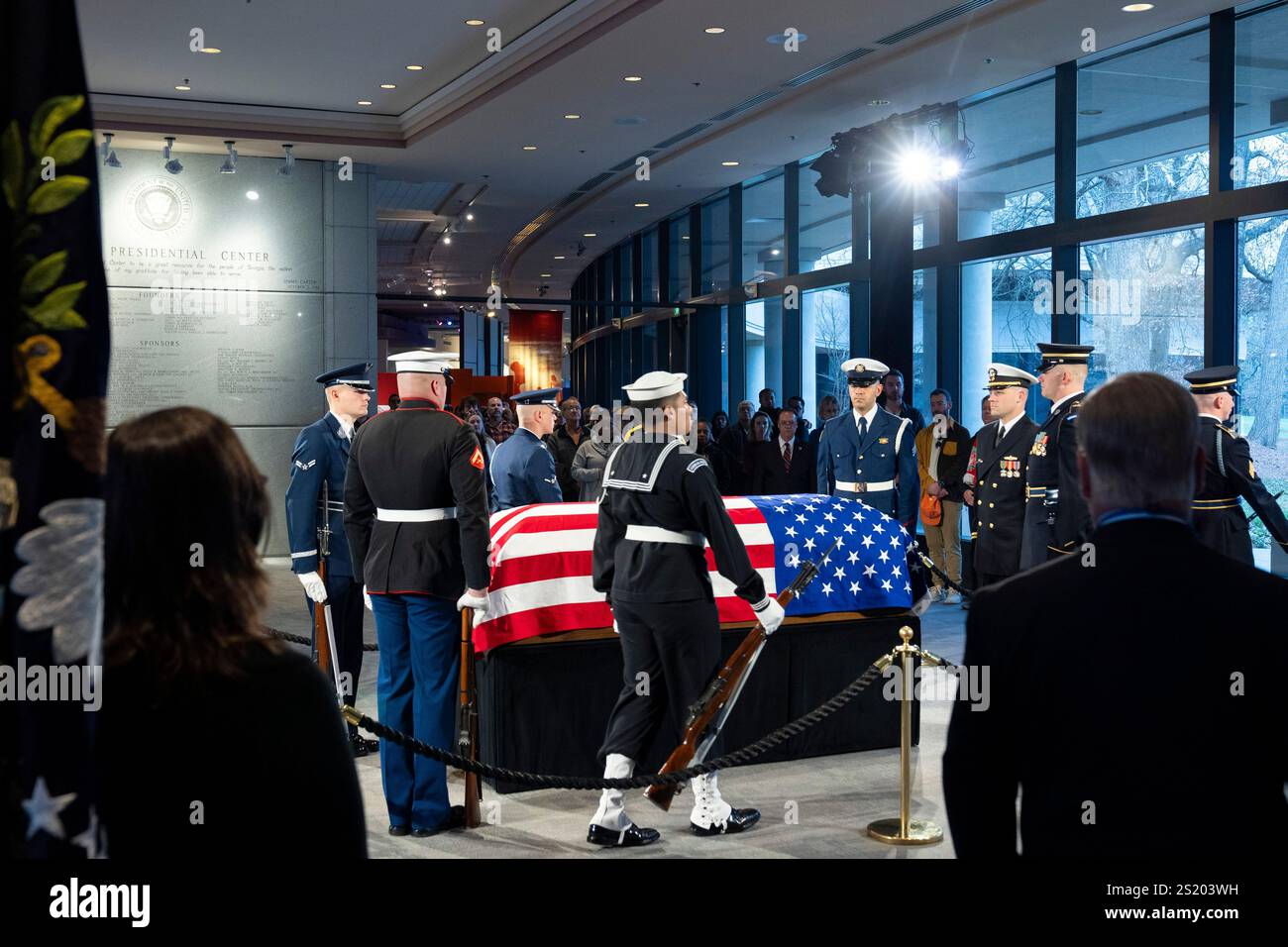 Mourners view the changing of guard of the joint services military honor guard as the casket of ...