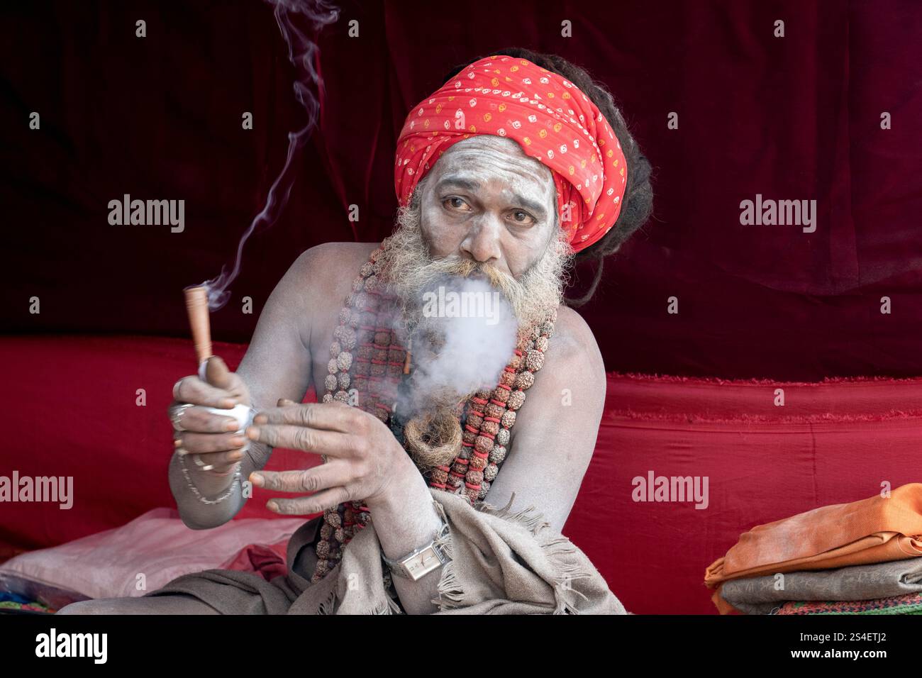 A Hindu holy man smokes marijuana at his makeshift living quarters at ...