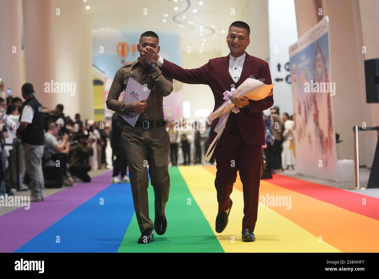 A just-married couple from the LGBTQ+ community walks on rainbow carpet ...