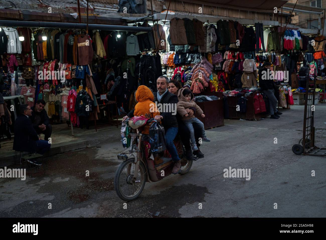 A family rides a motorbike through a local market in the northern ...