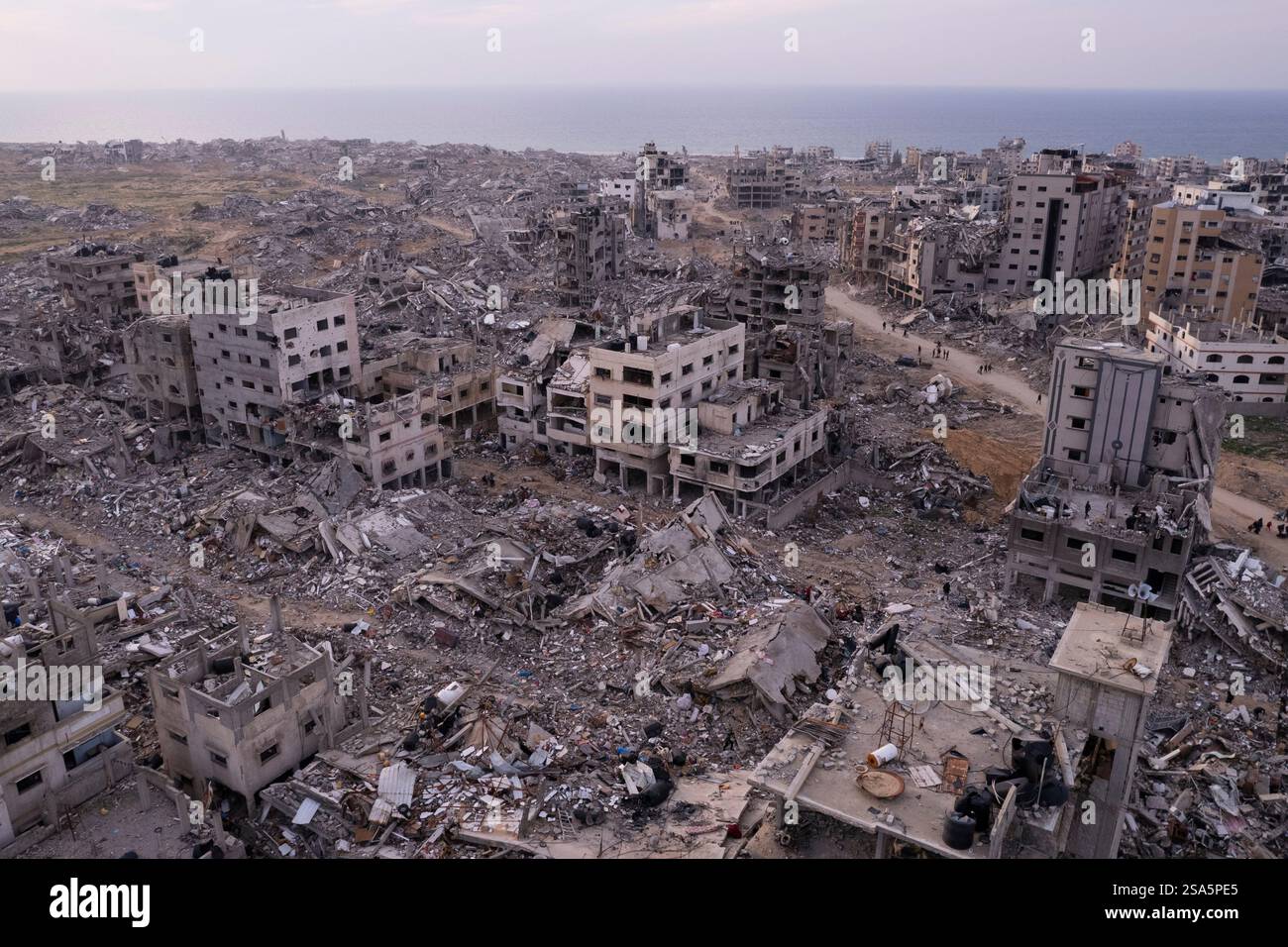 Palestinians walk through buildings that were destroyed by the Israeli ...