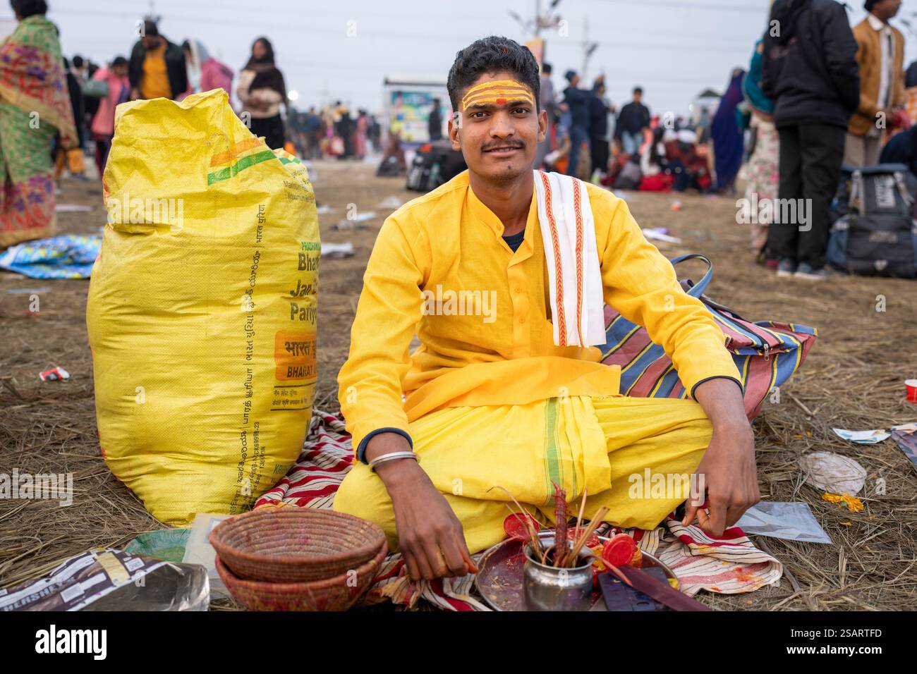 Hindu priest Anuj Kumar Tiwari, who puts sacred marks on devotees' foreheads, sits at his stall ...