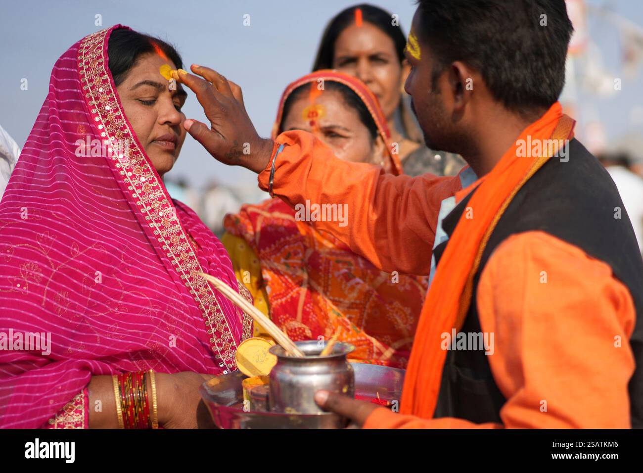 A Hindu priest puts a sacred mark on the forehead of a devotee at the ...