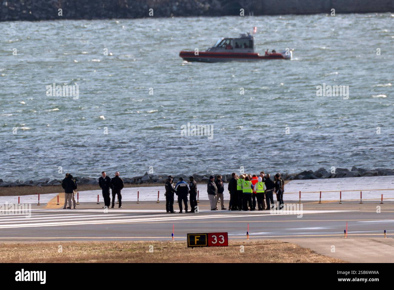 Officials gather at the end of runway 33 near the wreckage site in the ...