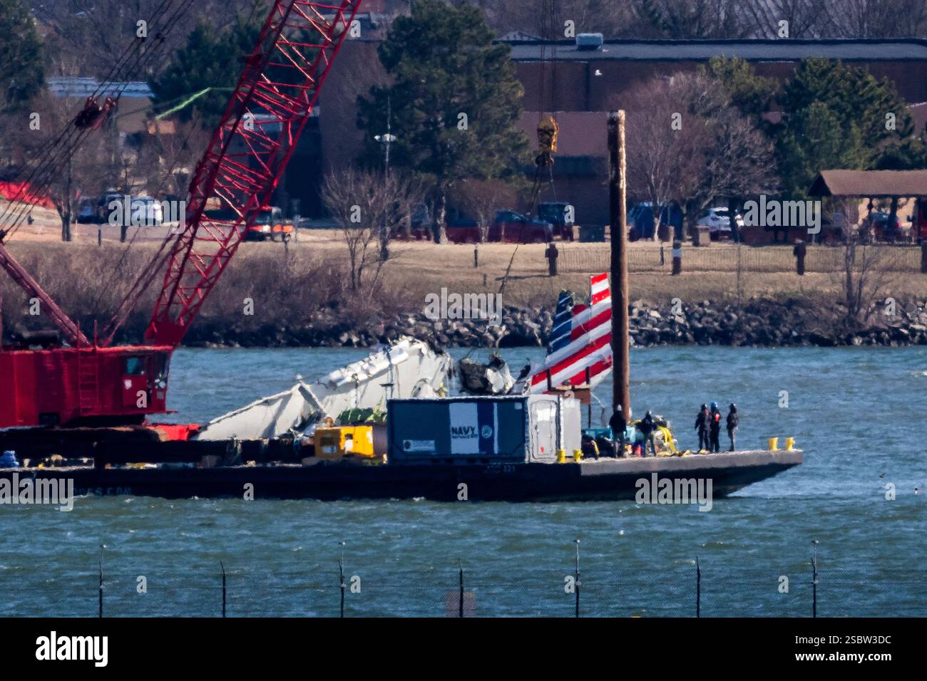 Parts of a plane are lifted from the water near the wreckage site in ...