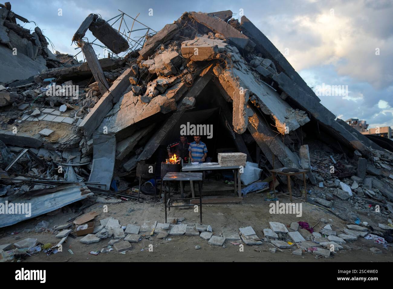A man sells bread under the destruction of his bakery destroyed by the ...