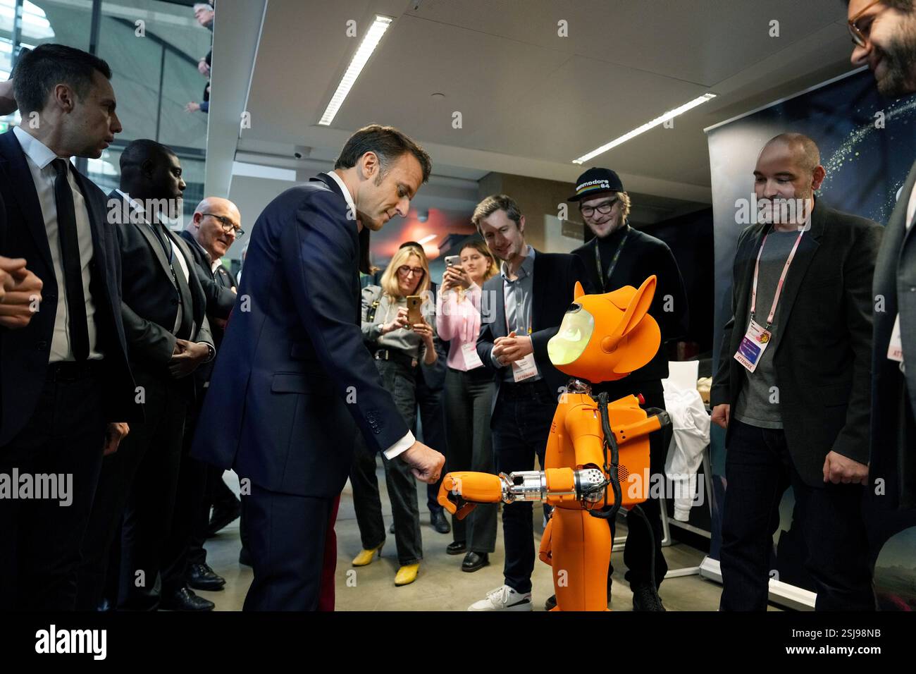 French President Emmanuel Macron, center left, bumps fists with a robot ...