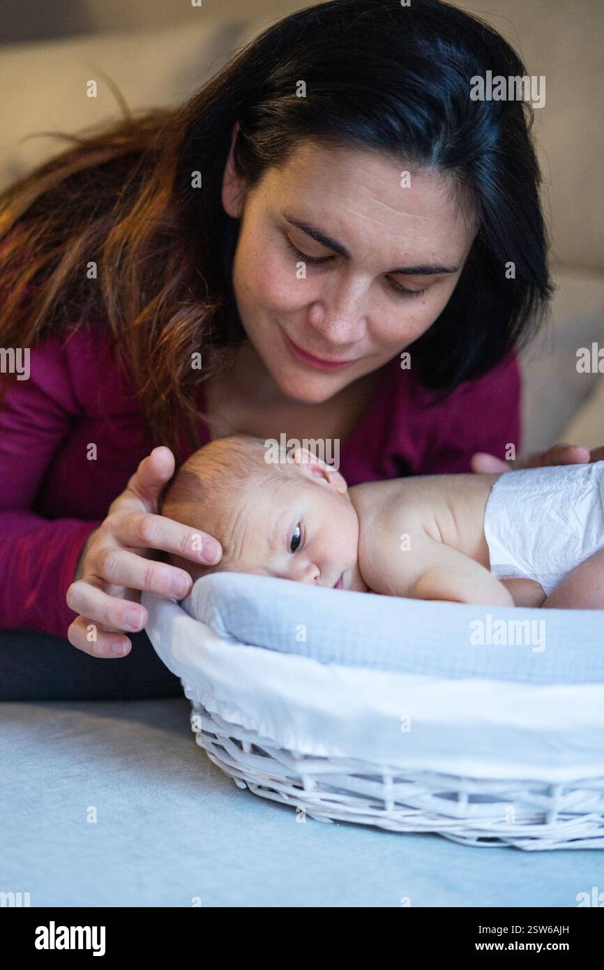 Liebevolle Mutter streichelt ihren neugeborenen Jungen, der in einem ...