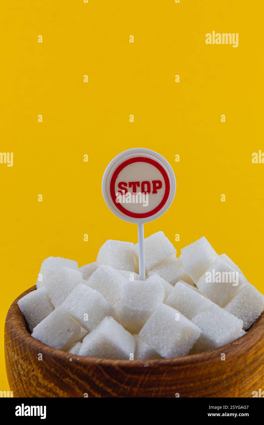 Eine Holzschale voller Zuckerwürfel ist mit einem hellen Stoppschild ...