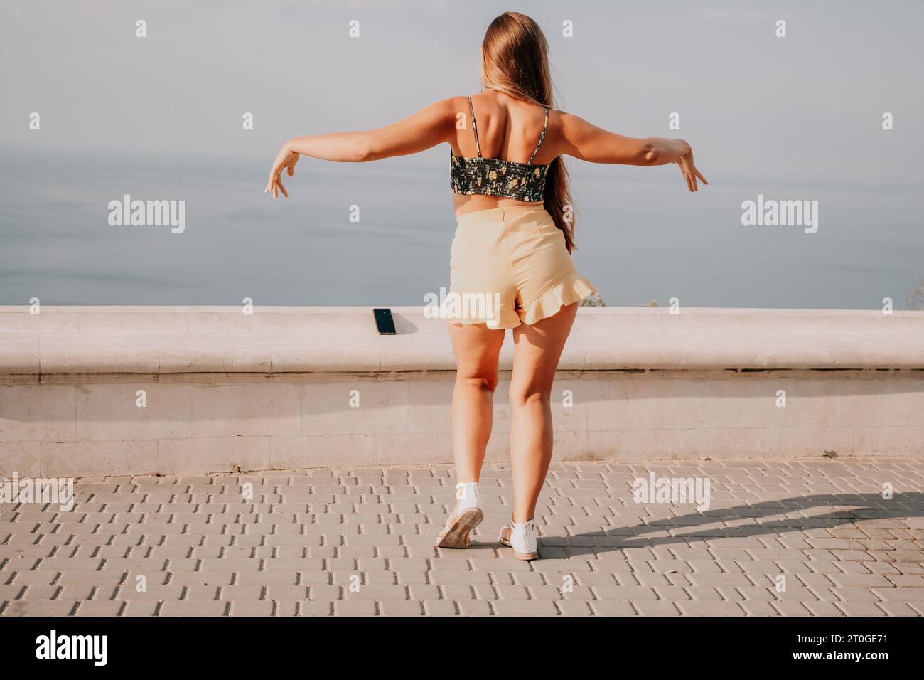 Frauen-Sommertanz. Silhouette einer glücklichen Frau, die tanzt, sich dreht und ihre Hände zum ...