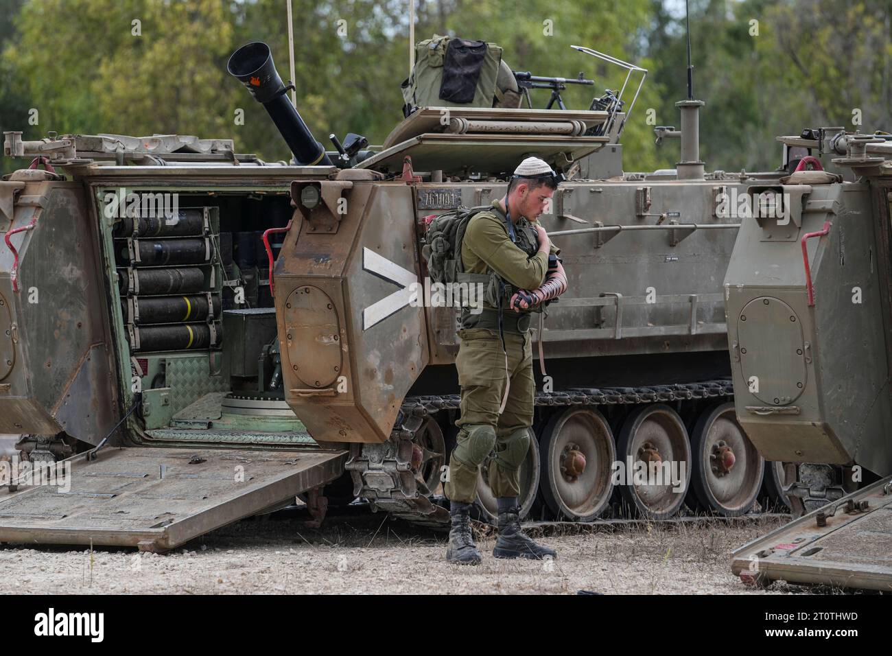 An Israeli soldier prays next to an APC at a staging ground near the ...