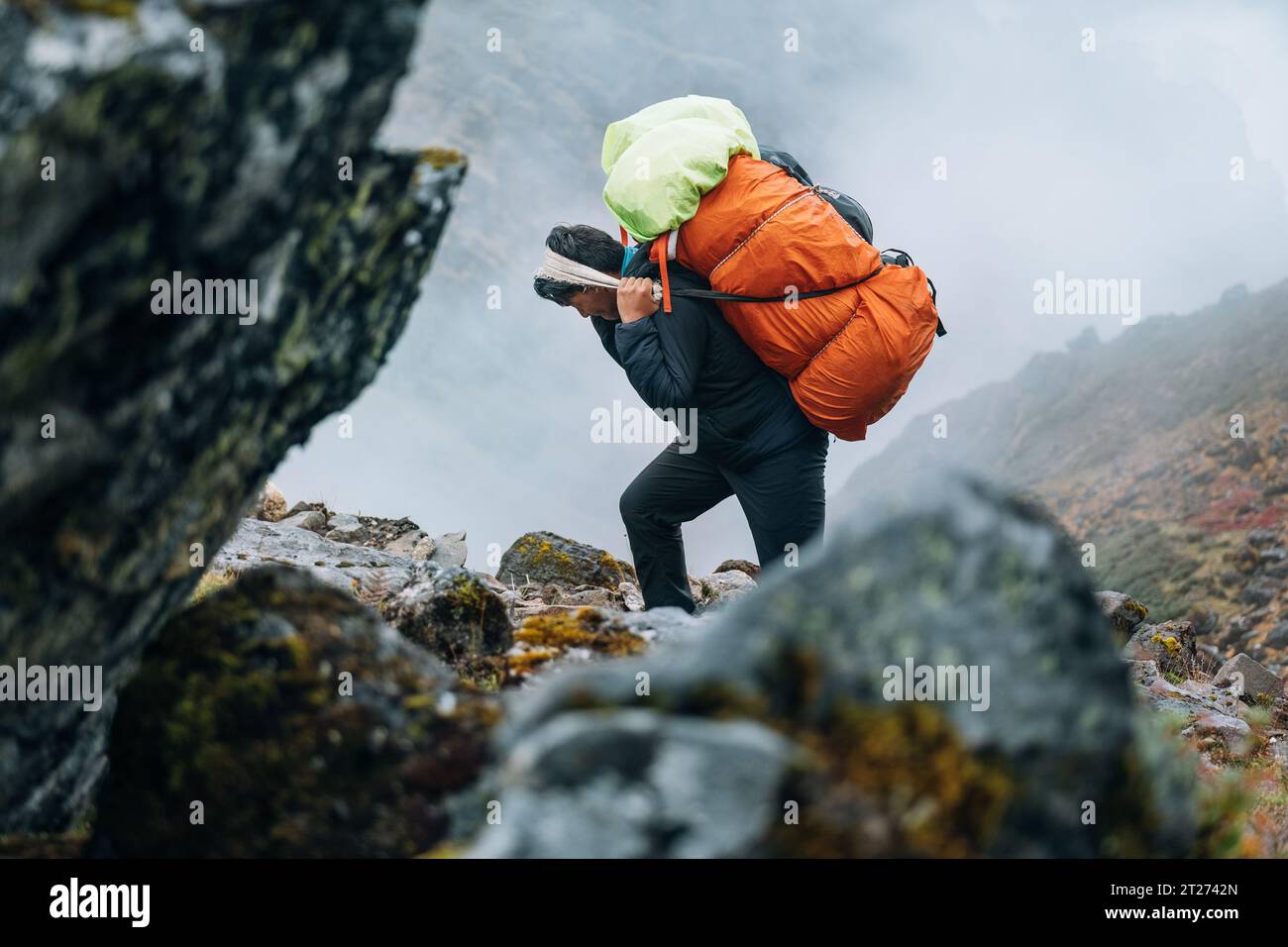 Starker Sherpa-Mann, der als Portier arbeitet und eine riesige Ladung ...
