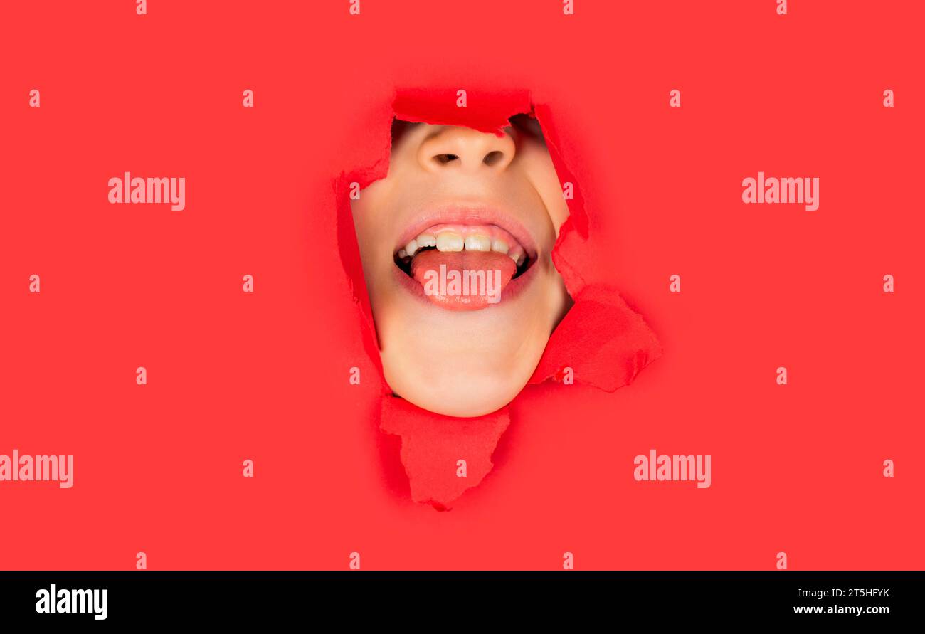 Das Kind streckte ihre Zunge durch ein Loch in das Papier. Boy zeigt ...