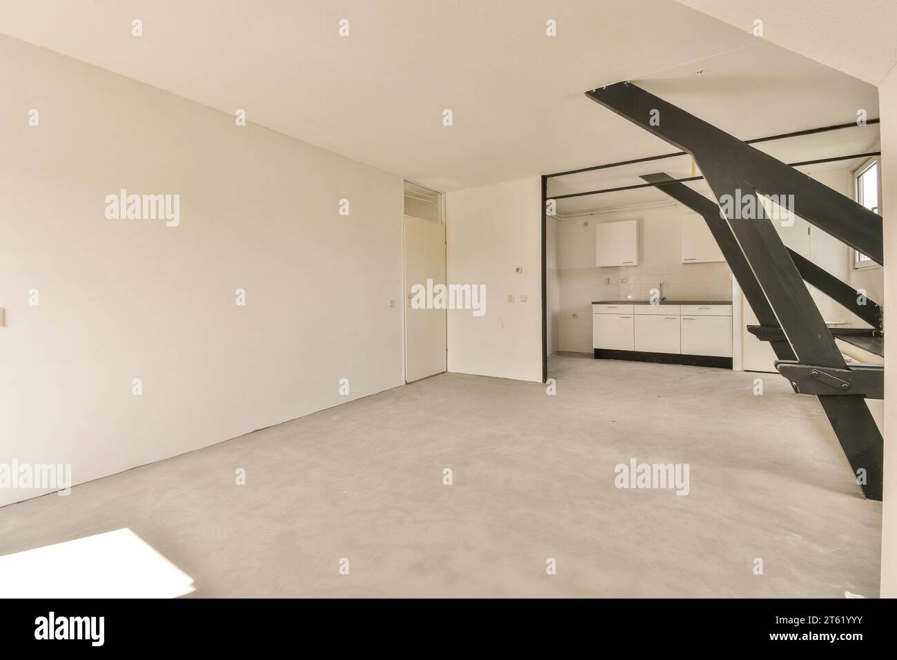 Ein leeres Wohnzimmer mit einer Treppe in den zweiten Stock und einer Küche in der Wand ist weiß ...