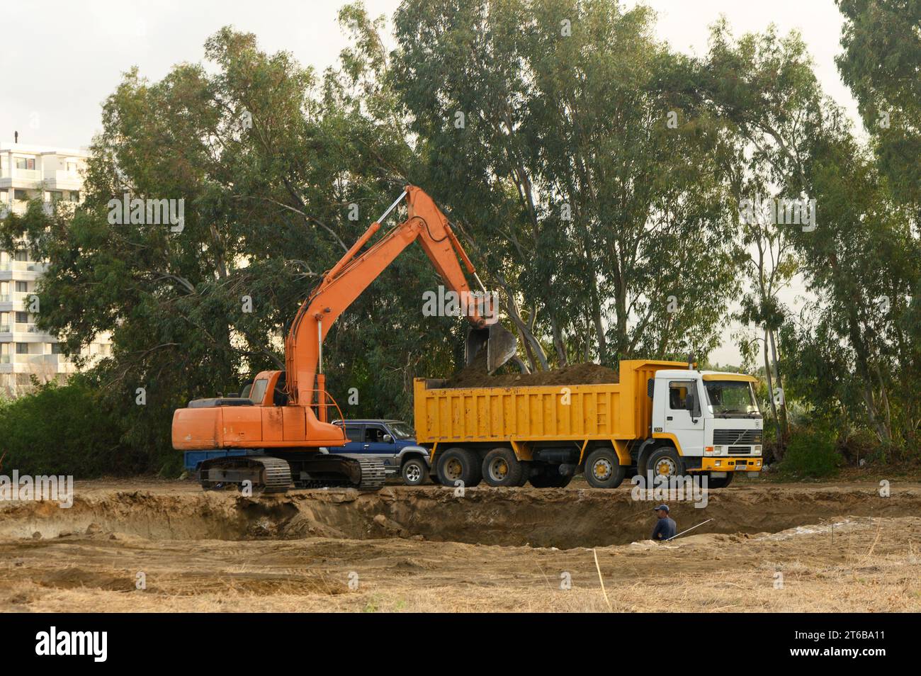 Ein Bagger gräbt ein Loch unter dem Fundament eines Hauses und lädt die ...