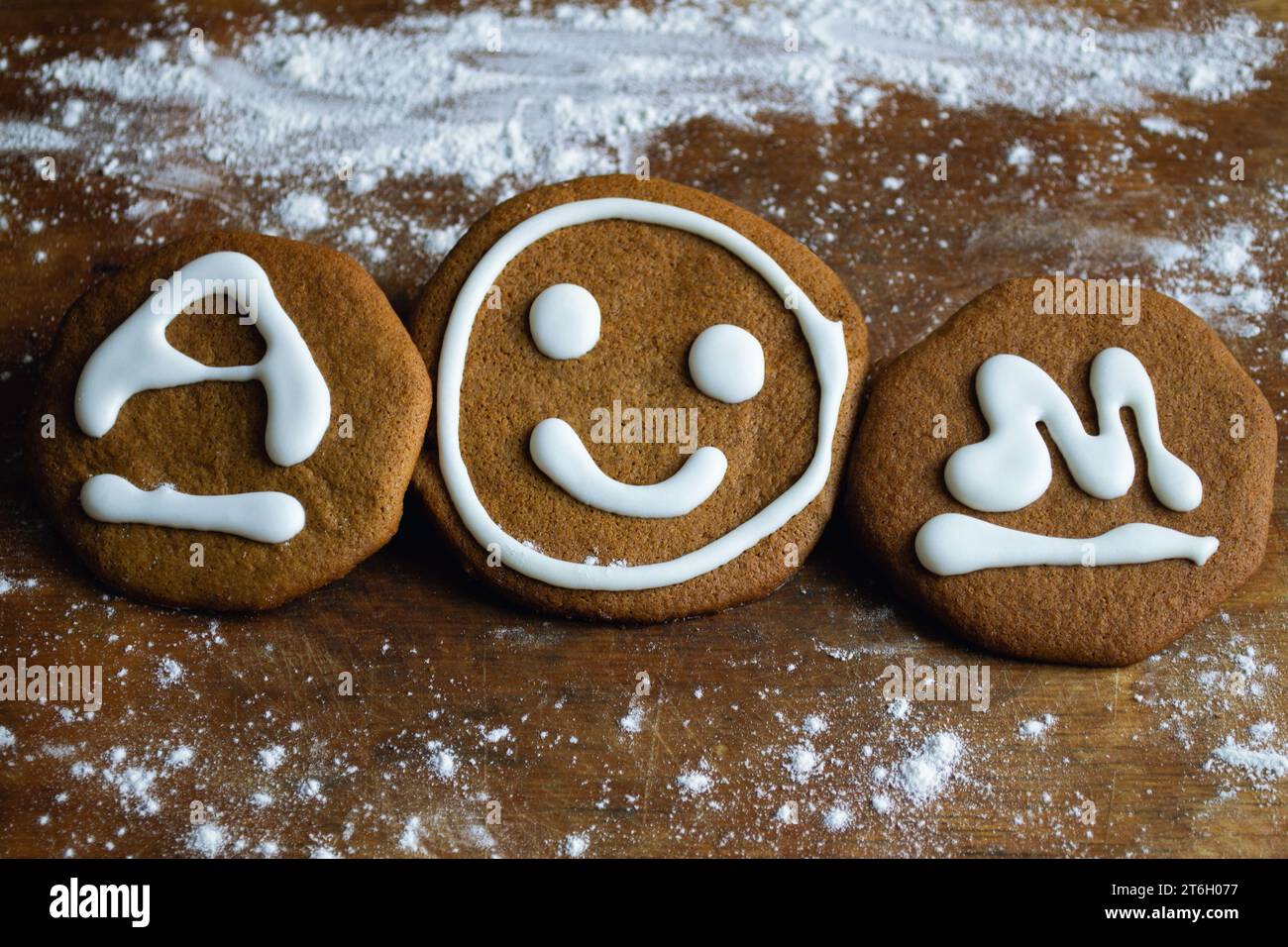 Drei süße Kekse, bedeckt mit weißer Glasur in Form eines Smileys und ...