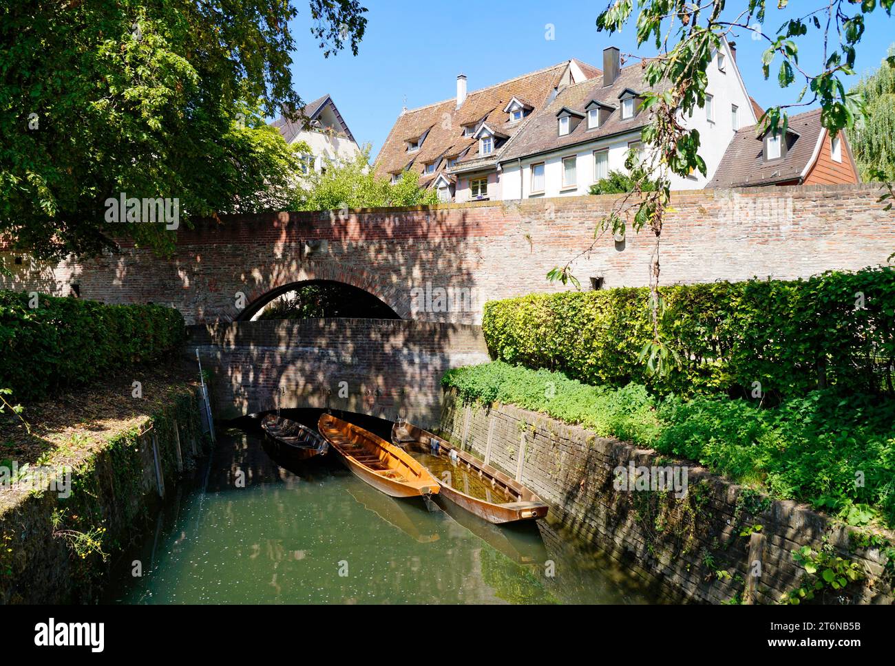 Eine malerische Aussicht auf eine kleine Brücke, darunter Holzboote ...