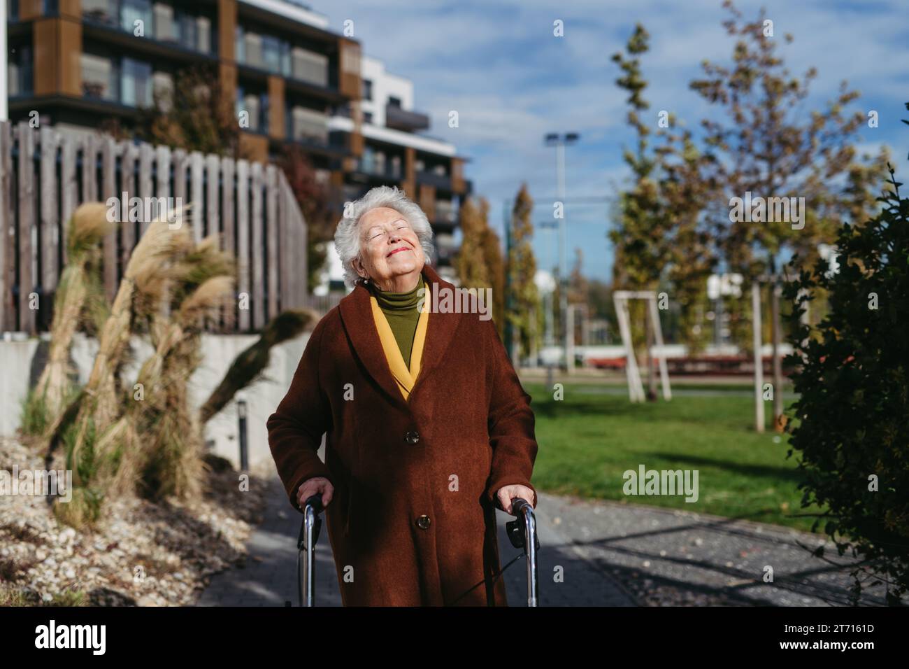 Seniorin mit einem Gehhilfen, der am Herbsttag auf den Straßen der ...