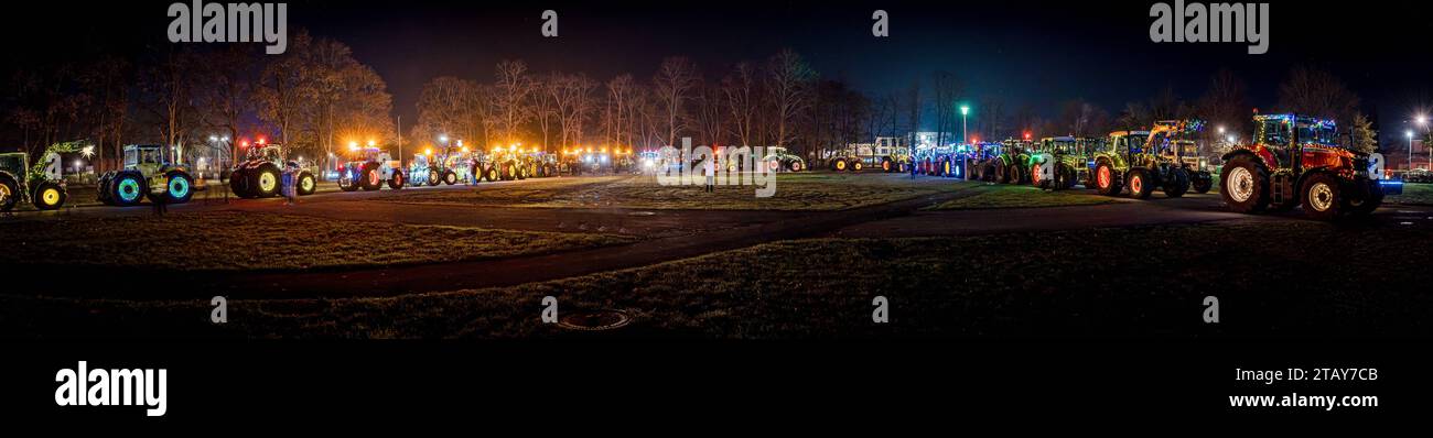 Lichterfahrt - viele mit bunten Lichterketten geschmückte Traktoren am Abend auf einem ...