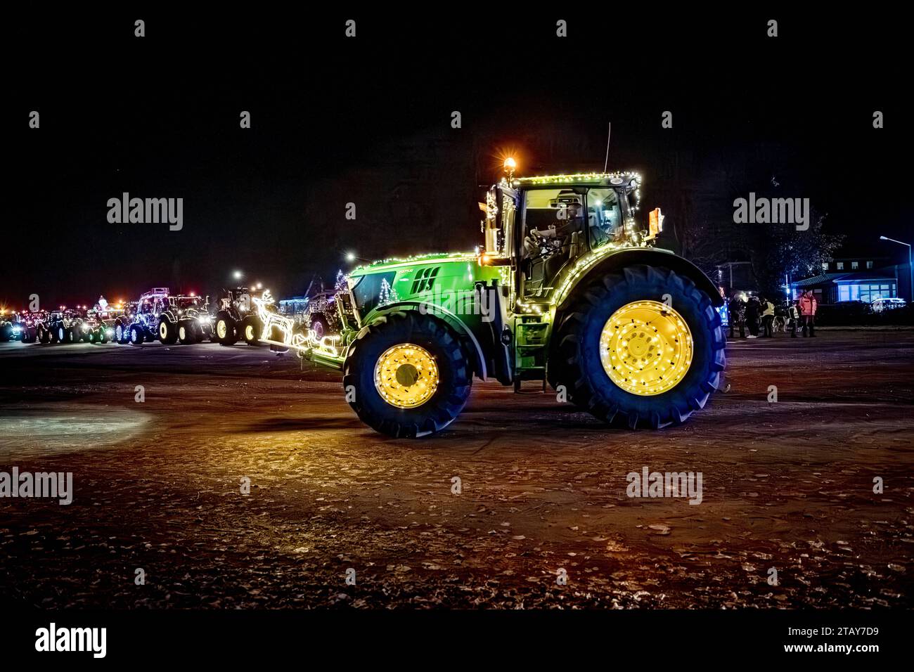 Lichterfahrt - grüner mit weihnachtlichen Lichterketten geschmückter Traktor fährt auf einem ...