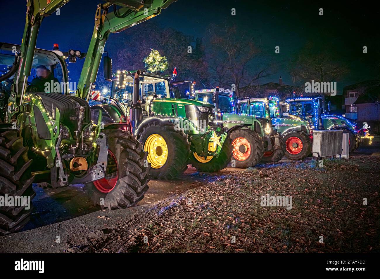 Lichterfahrt - mit bunt leuchtenden Lichterketten geschmückte Traktoren stehen auf einem ...