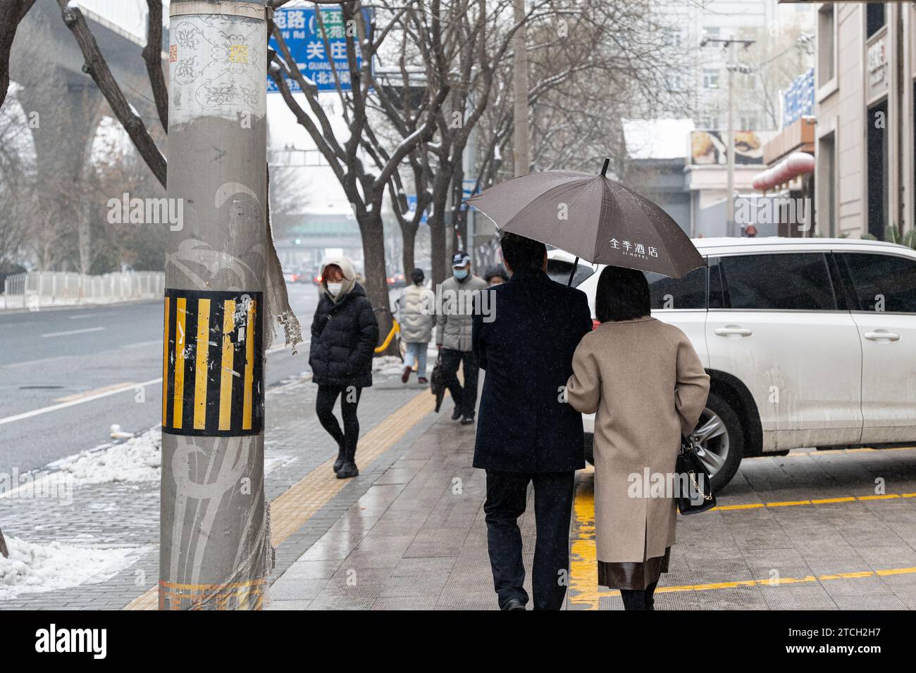 Peking, China. Dezember 2023. Ein Paar, das unter einem Regenschirm im ...