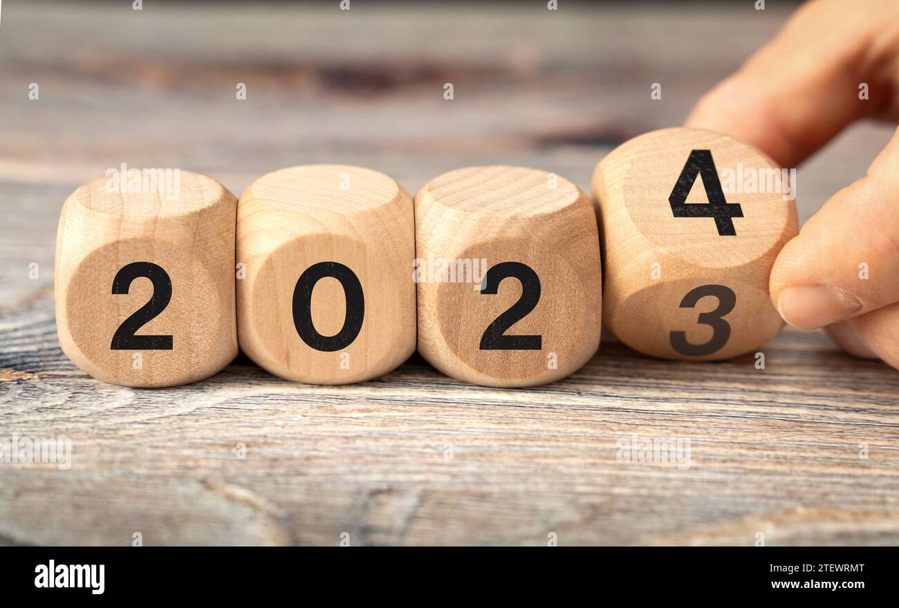 19. Dezember 2023: Jahreswende von 2023 bis 2024 und Silvesterkonzept. Hand dreht Holzwürfel zum ...