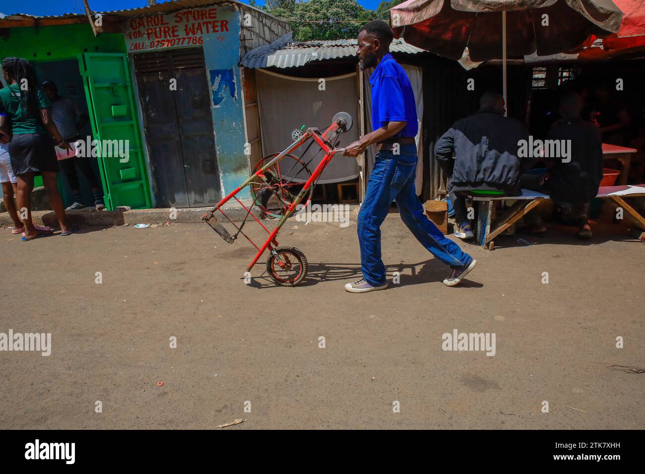 Ein cutler fährt mit seiner Maschine durch die Straßen von Kibera Slum ...