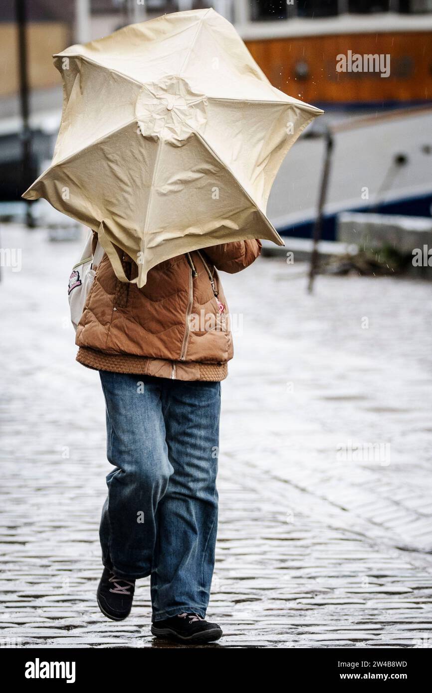 Touristen, die ihre Regenschirme halten, kämpfen mit dem Wind, während ...