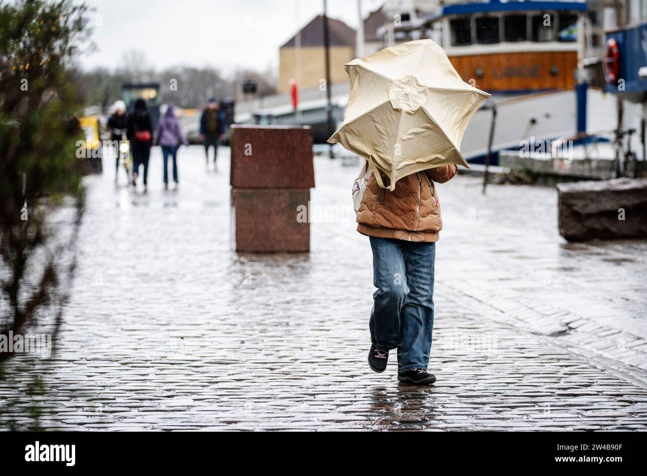 Touristen, die ihre Regenschirme halten, kämpfen mit dem Wind, während ...