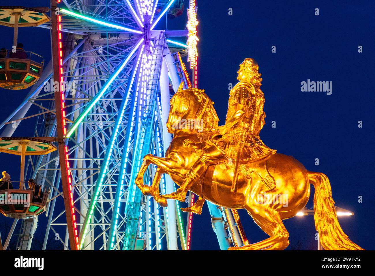 Das Denkmal Goldener Reiter steht in der Daemmerung vor einem Riesenrad ...