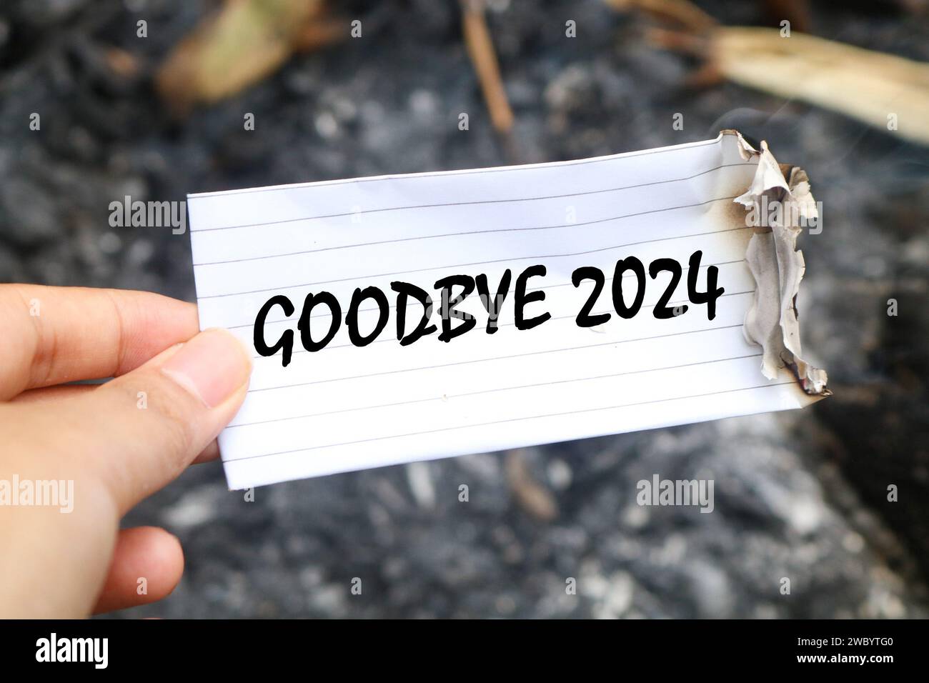 Hand hält halb verbrannte Notiz mit Aufschrift Bye 2024. Neues Leben und neues Jahr 2024-Konzept ...