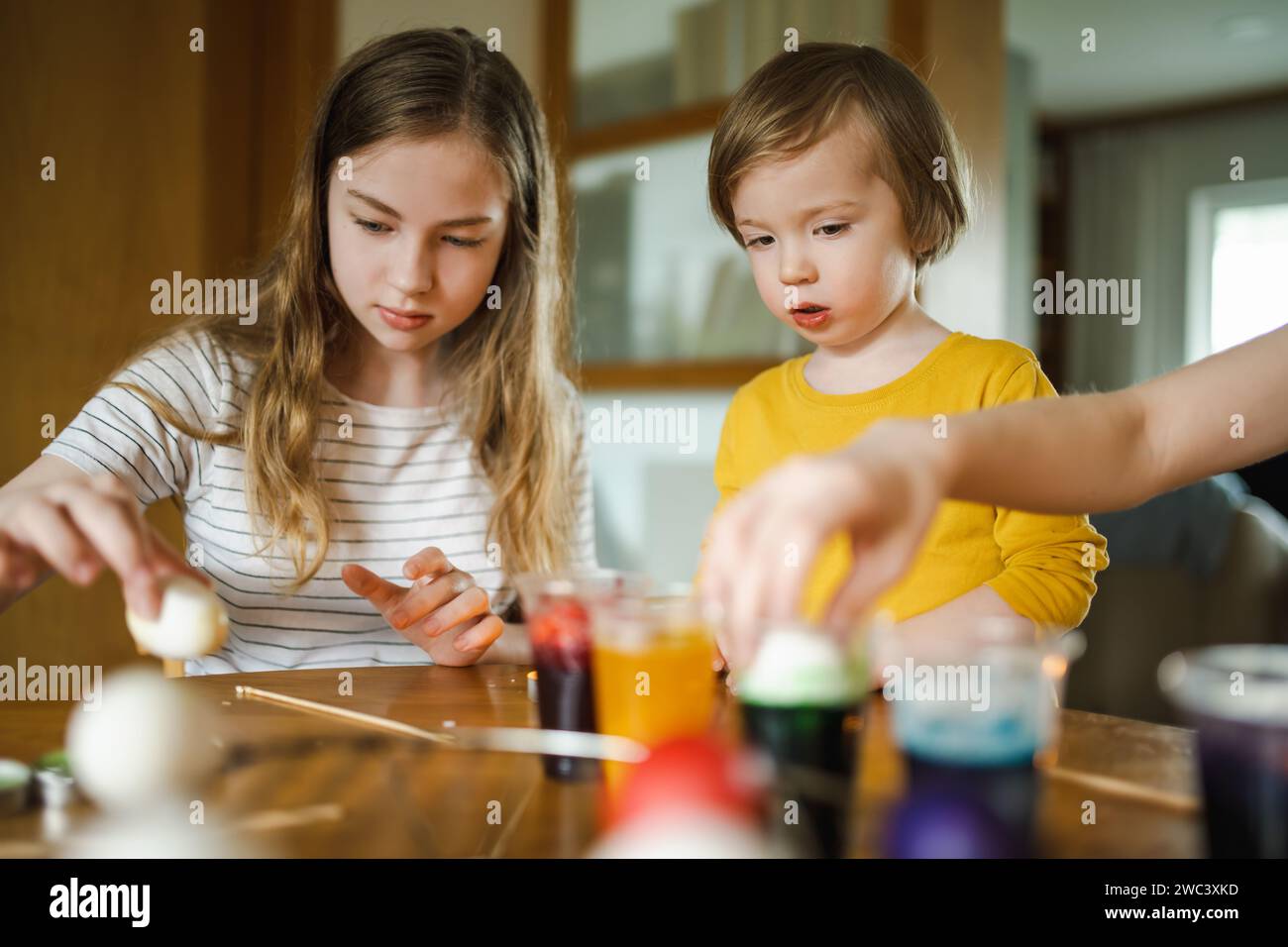 Große Schwester und ihr kleiner Bruder färben Ostereier zu Hause ...