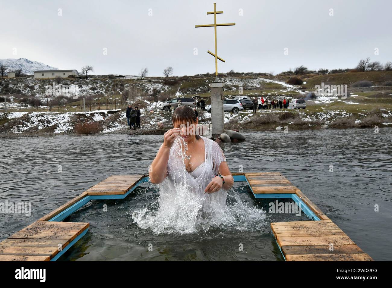 A woman crosses herself as she bathes into the cold mountain river Kara ...