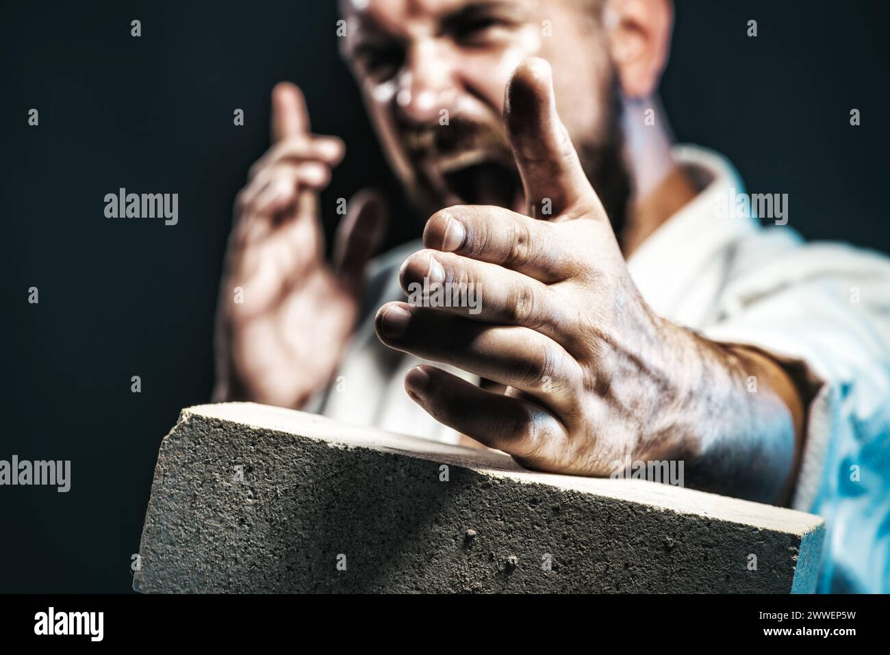 Karatemeister bricht Betonziegel mit der Hand. Karate-Kämpfer zeigt ...