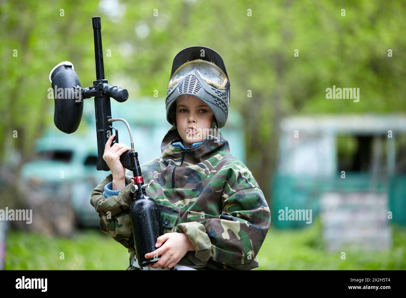 Der Junge in der Tarnung hält ein Paintball-Gewehrlauf hoch und sagt ... Der Junge in der Tarnung hält ein Paintball-Gewehrlauf hoch und sagt ...