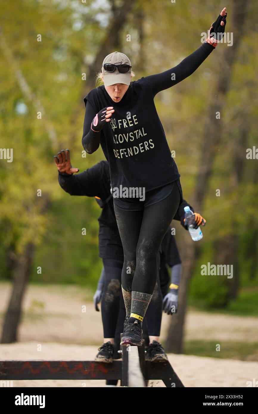 Junge Frauen laufen auf einer Balkenplanke beim Spartan Race ...