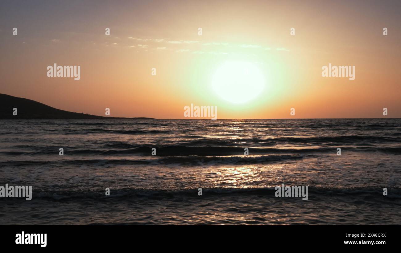 Die Sonne untergeht über dem Meer und strahlt ein warmes Licht auf das ...
