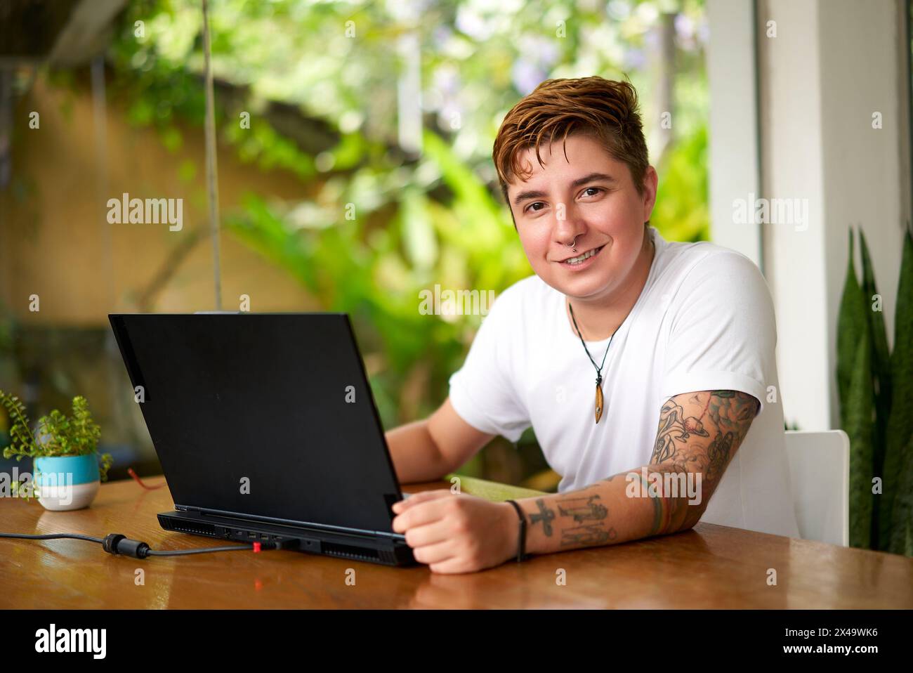 Der sichere Transgender-Pro arbeitet in umweltfreundlichen Büros mit einem Notebook. Lächelnd ...