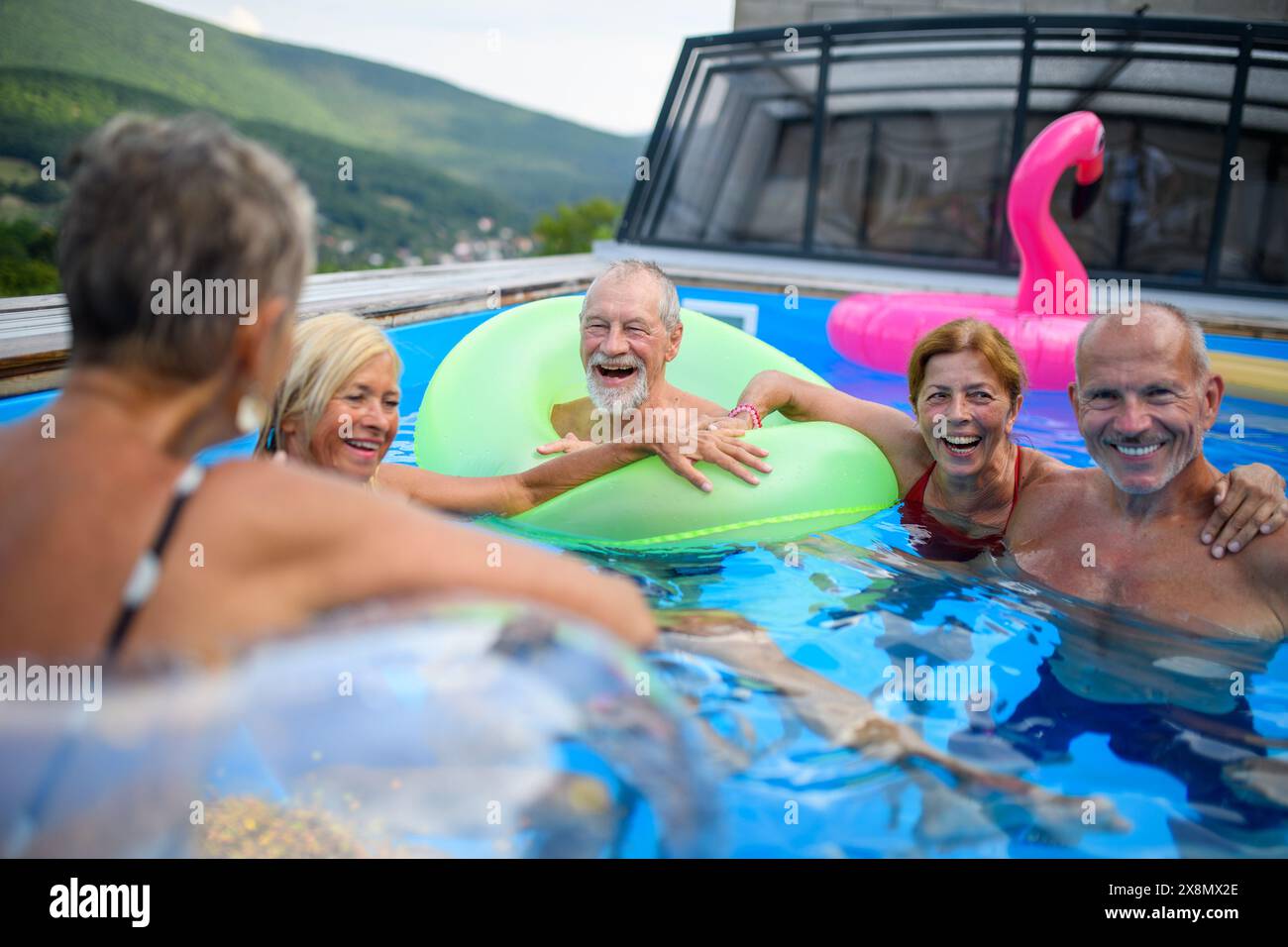 Gruppe von fröhlichen Senioren, die Spaß beim Springen im Pool ...