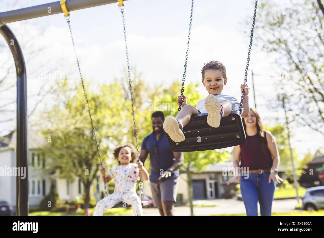 Spielmomente. Familie mit Kind Schaukeln und Spaß auf dem Spielplatz ...