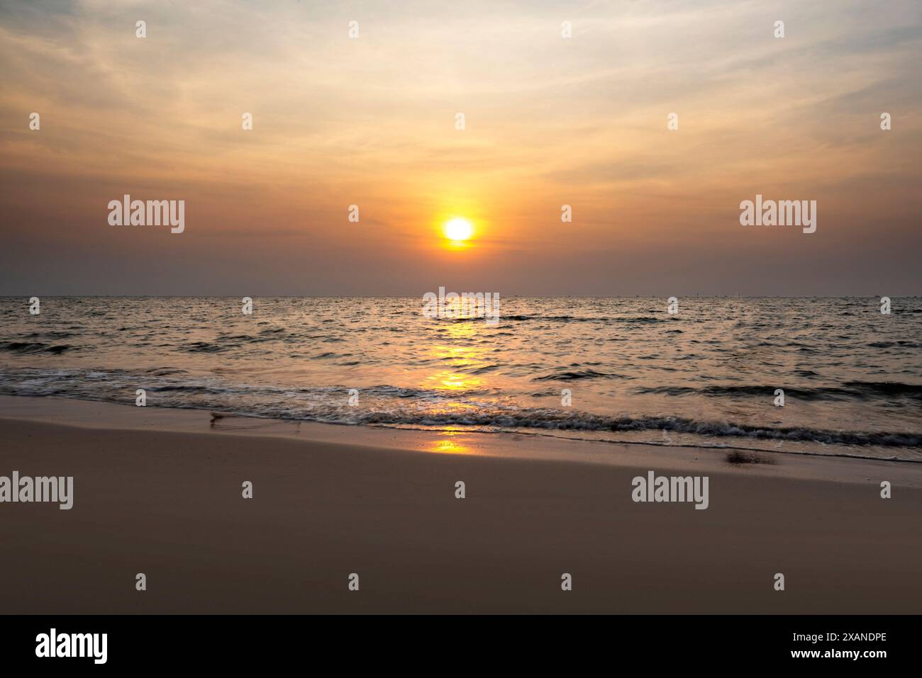 Die Sonne untergeht über dem Meer und strahlt ein warmes Licht auf das ...