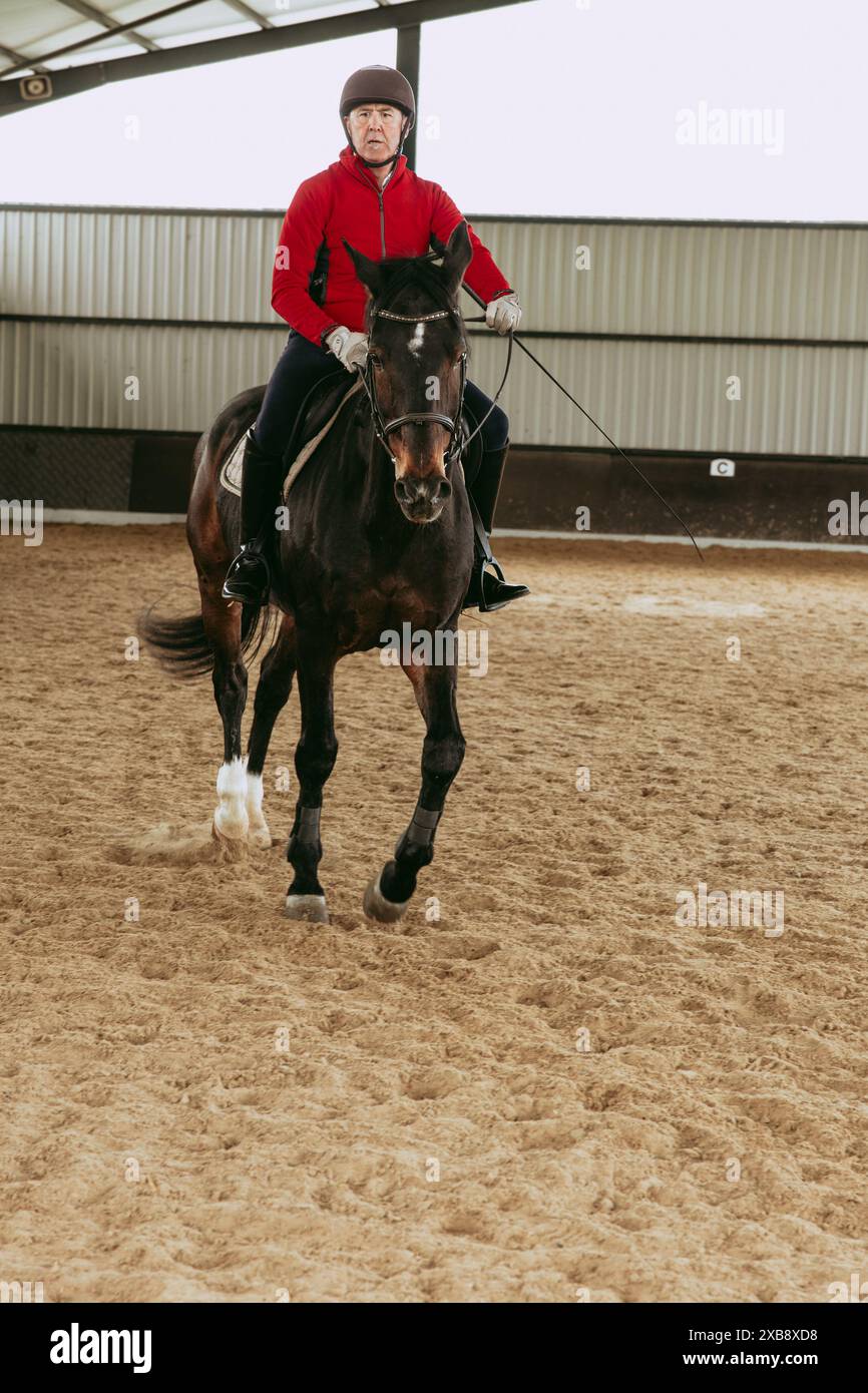 Ein pensionierter Mann, der sein Hobby des Reitens in einer Halle ...