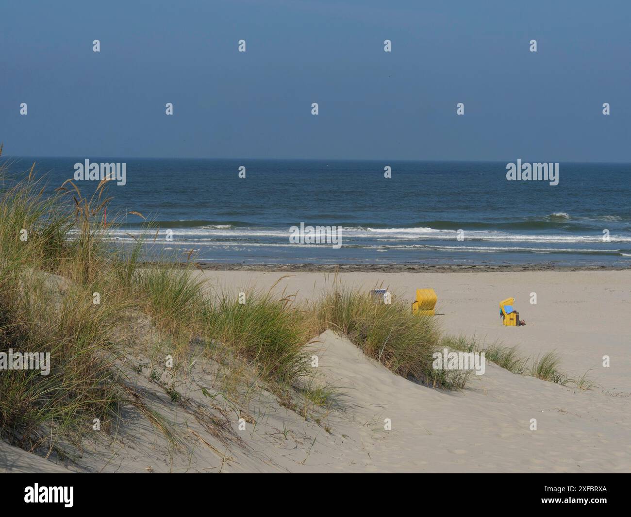 Blick durch grasbewachsene Dünen auf den Strand und das Meer mit Wellen ...