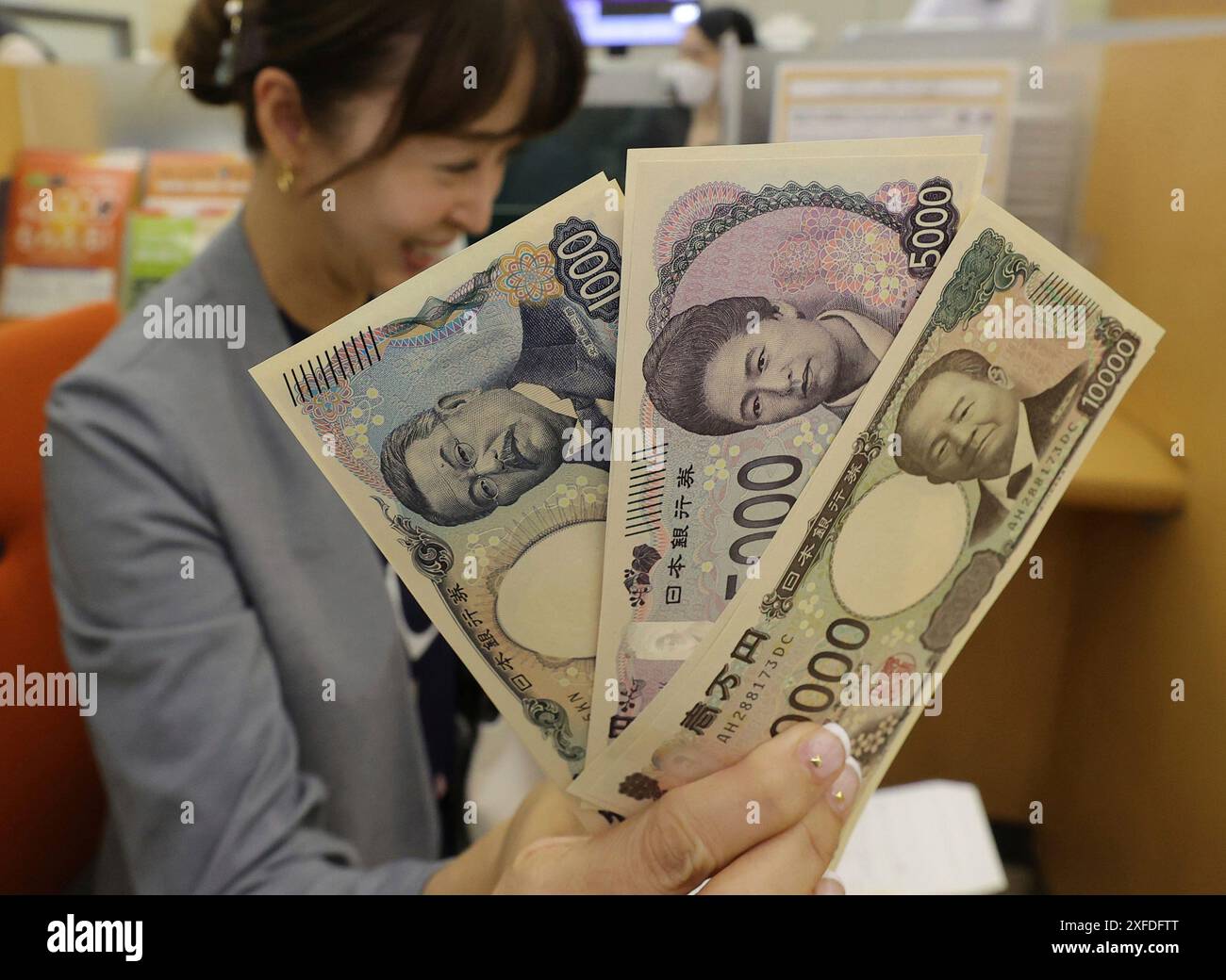 A woman shows three types of new banknotes which were issued for the ...